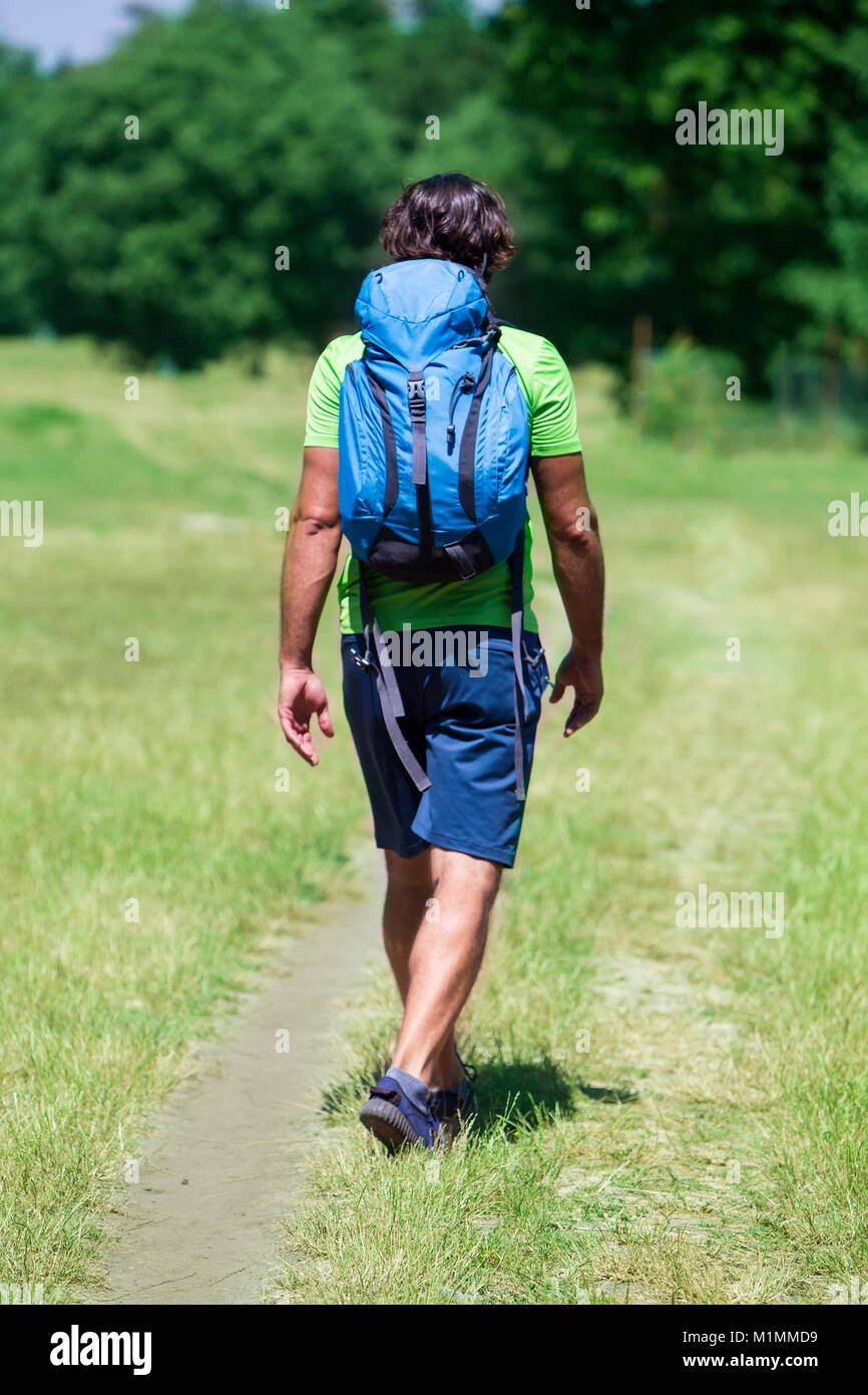 Back view at young man with backpack hiking at green nature Stock Photo ...