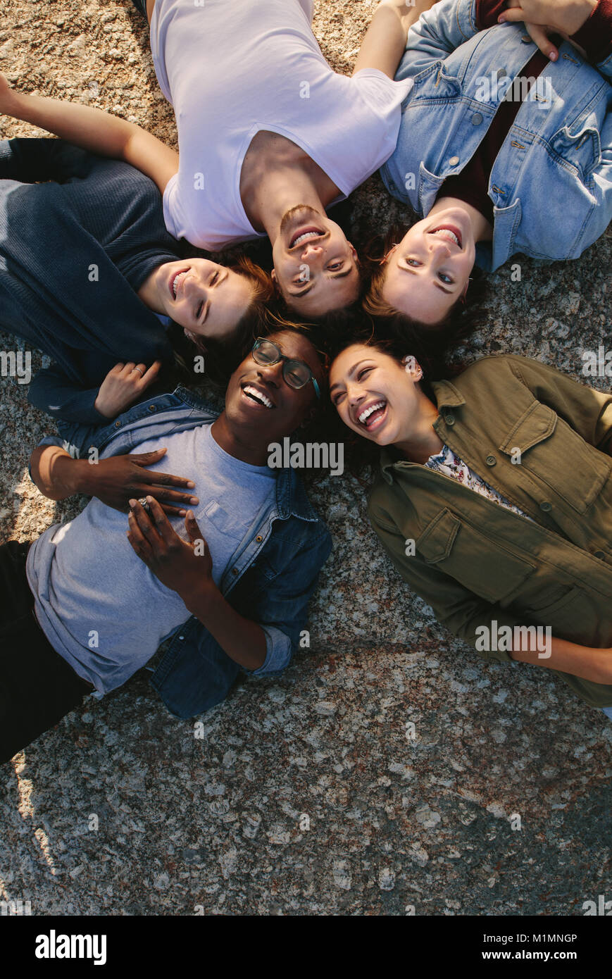 Group of diverse friends lying on ground in circle outdoors. Men and ...
