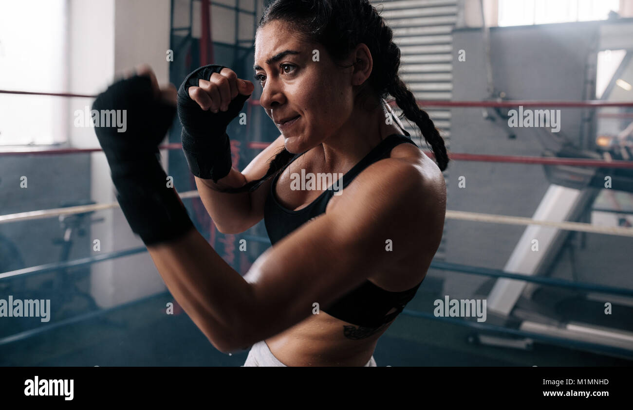 Close up of a female boxer doing shadow boxing inside a boxing ring ...