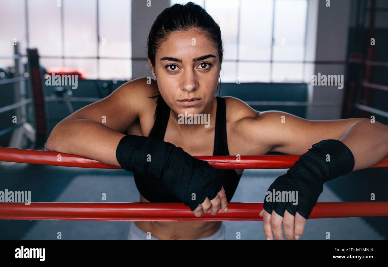 Close up of a female boxer standing inside a boxing ring. Boxer resting ...