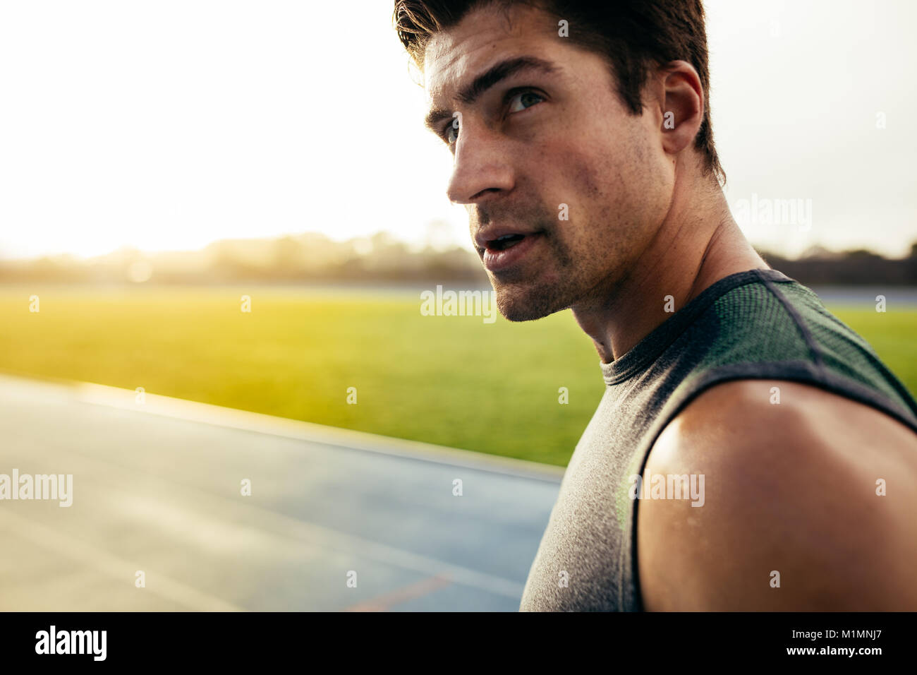 Closeup of a sprinter standing on a running track. Athlete looking away ...