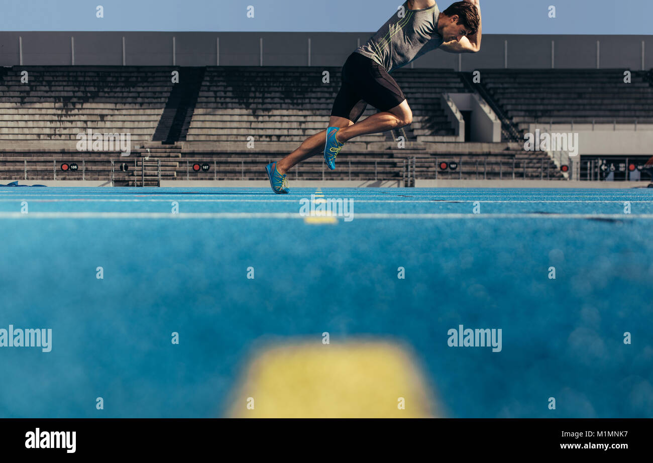 Side view of an athlete starting his sprint on an all-weather running ...