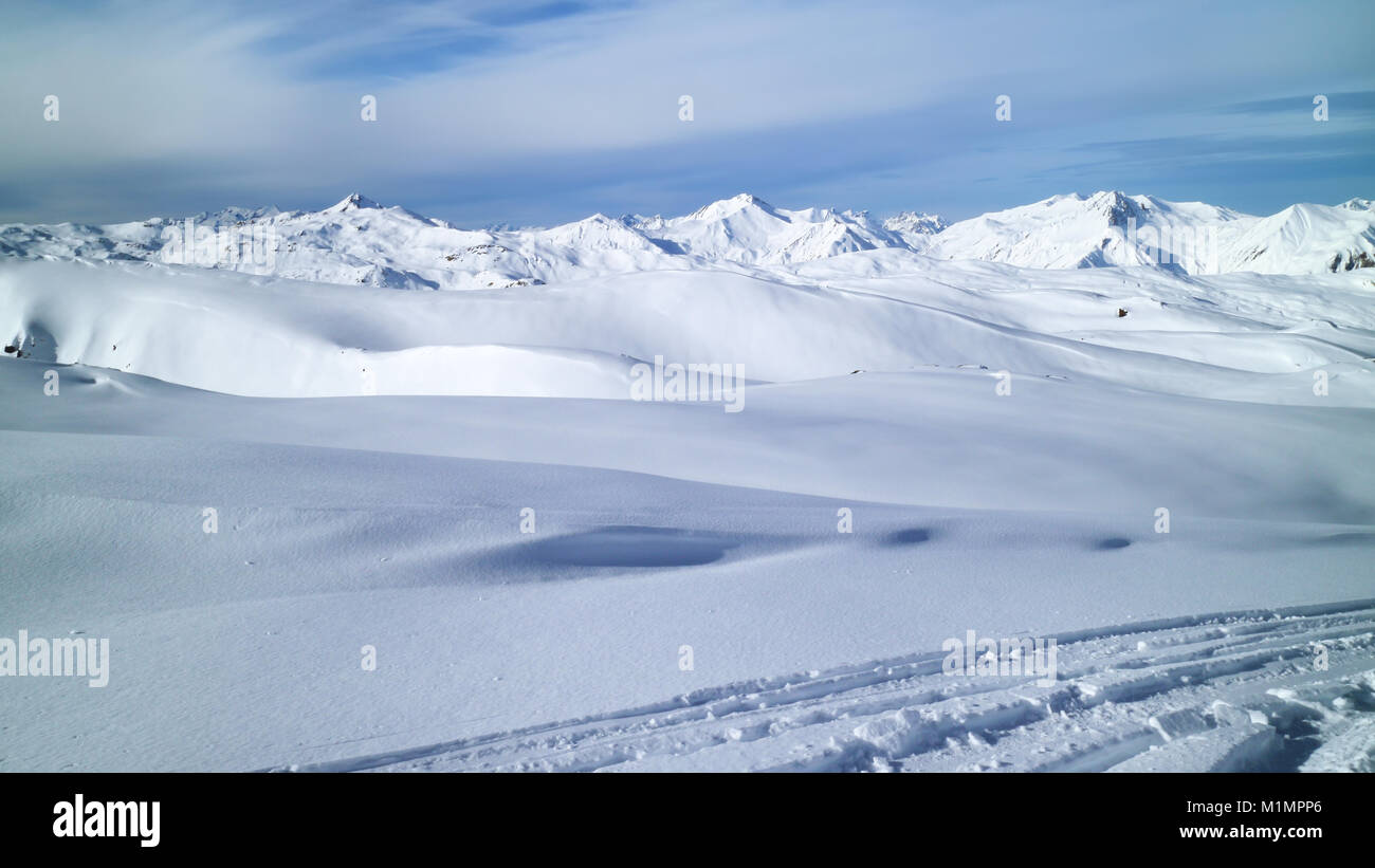 Fresh snow on ski pistes, covering valleys and peaks, with rugged ...