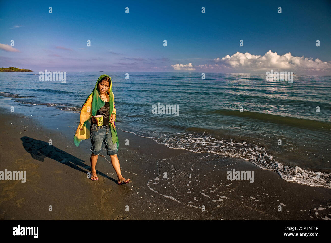 A young Filipino woman takes a morning walk drinking her coffee in a ...