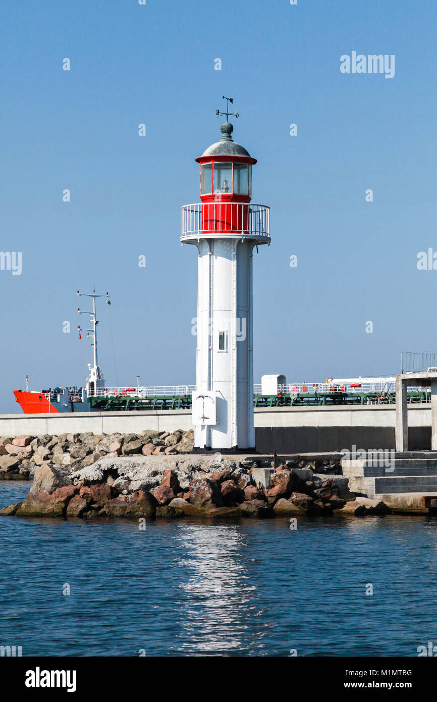 White lighthouse tower with red top stands on the entrance breakwater ...