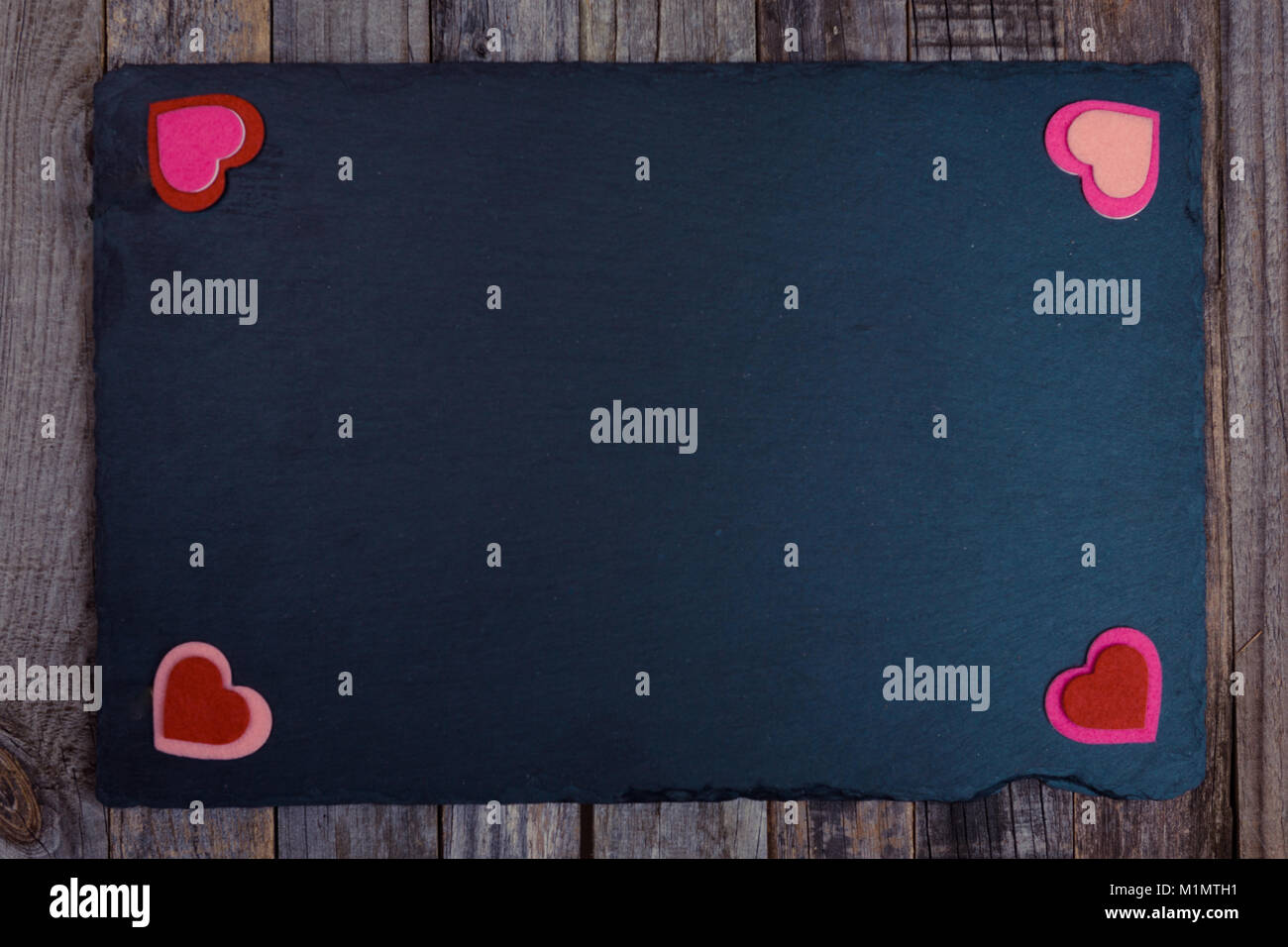 Slate stone board with colorful hearts on vintage wooden background ...