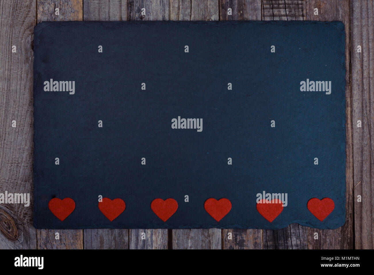 Slate stone board with colorful hearts on vintage wooden background ...