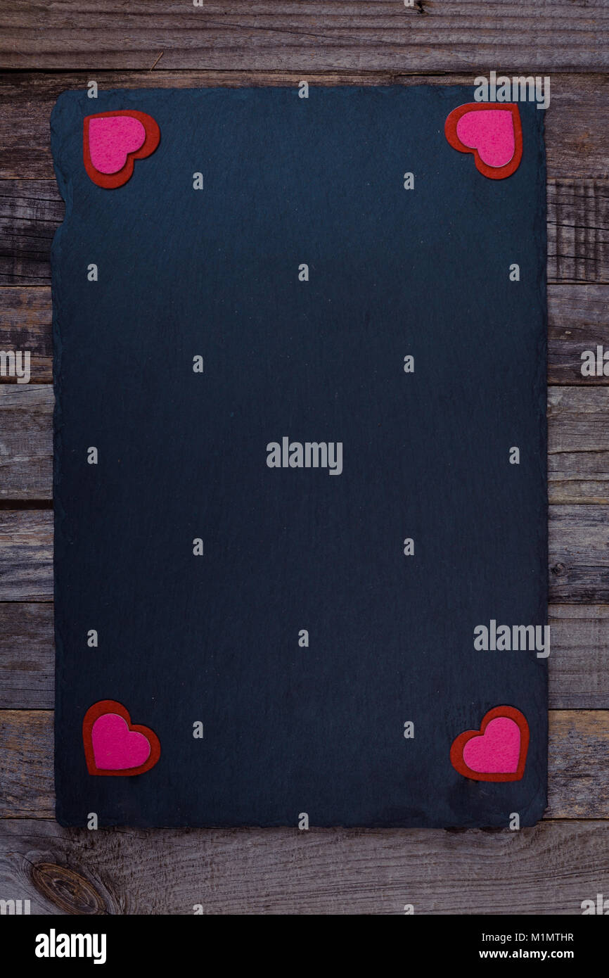 Slate stone board with colorful hearts on vintage wooden background ...