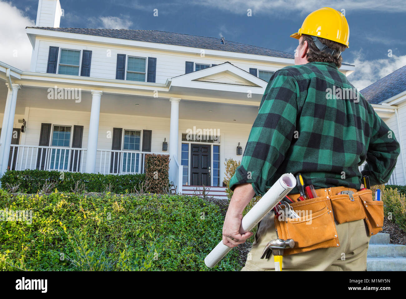 Male Contractor with Hard Hat and Tool Belt Looking At Custom House ...