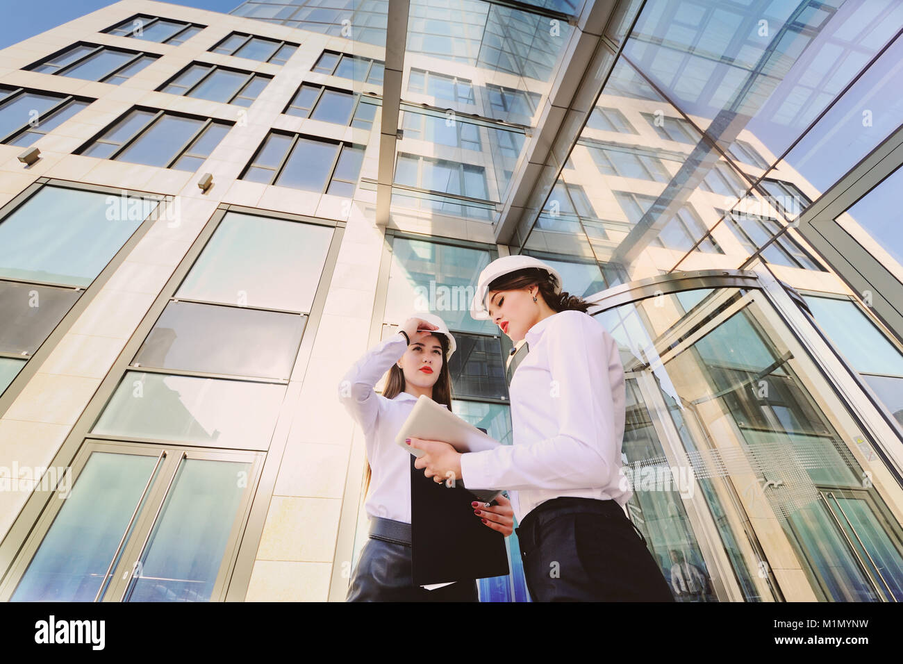 Two young pretty business women industrial engineers in construction ...