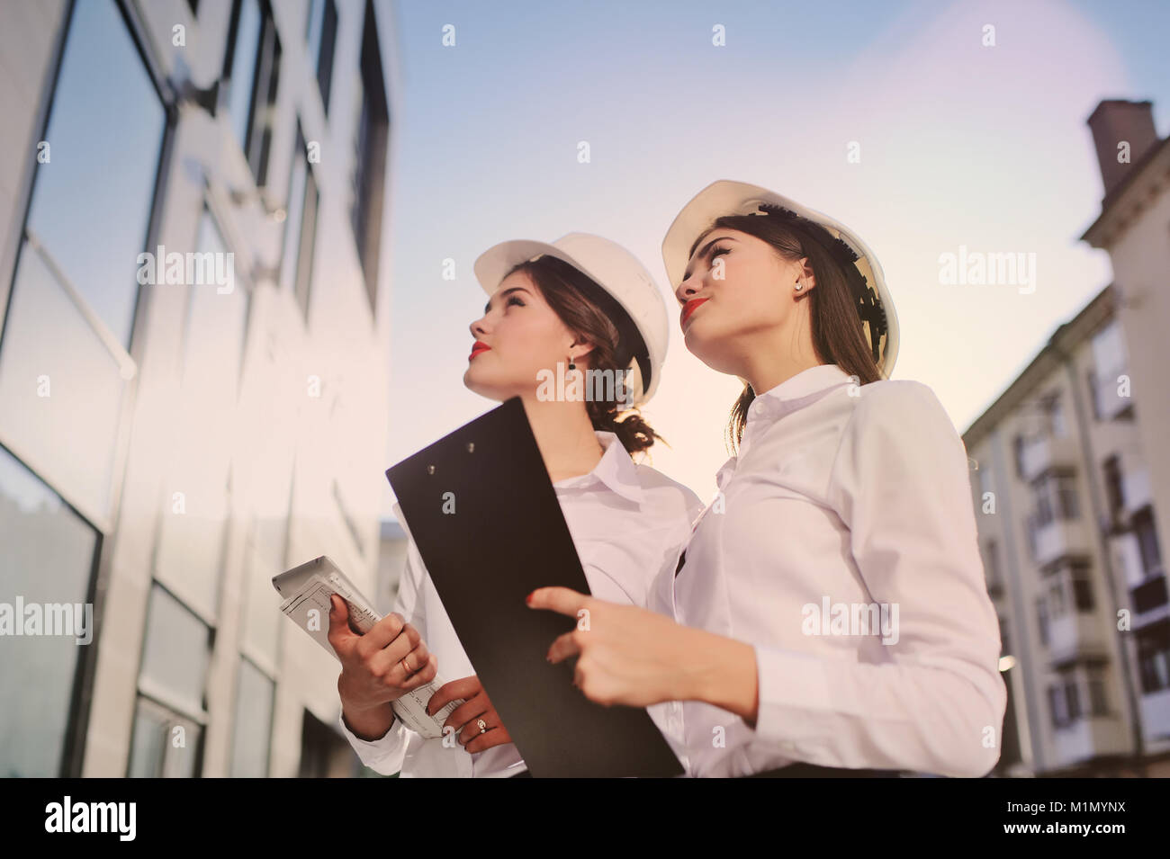 Two young pretty business women industrial engineers in construction ...