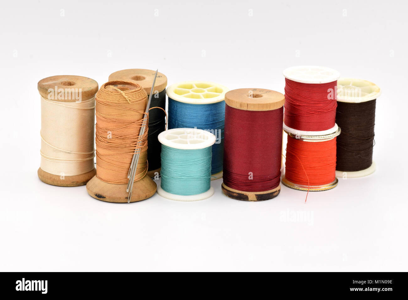 Assorted spools of colorful thread arranged on a seamless white ...