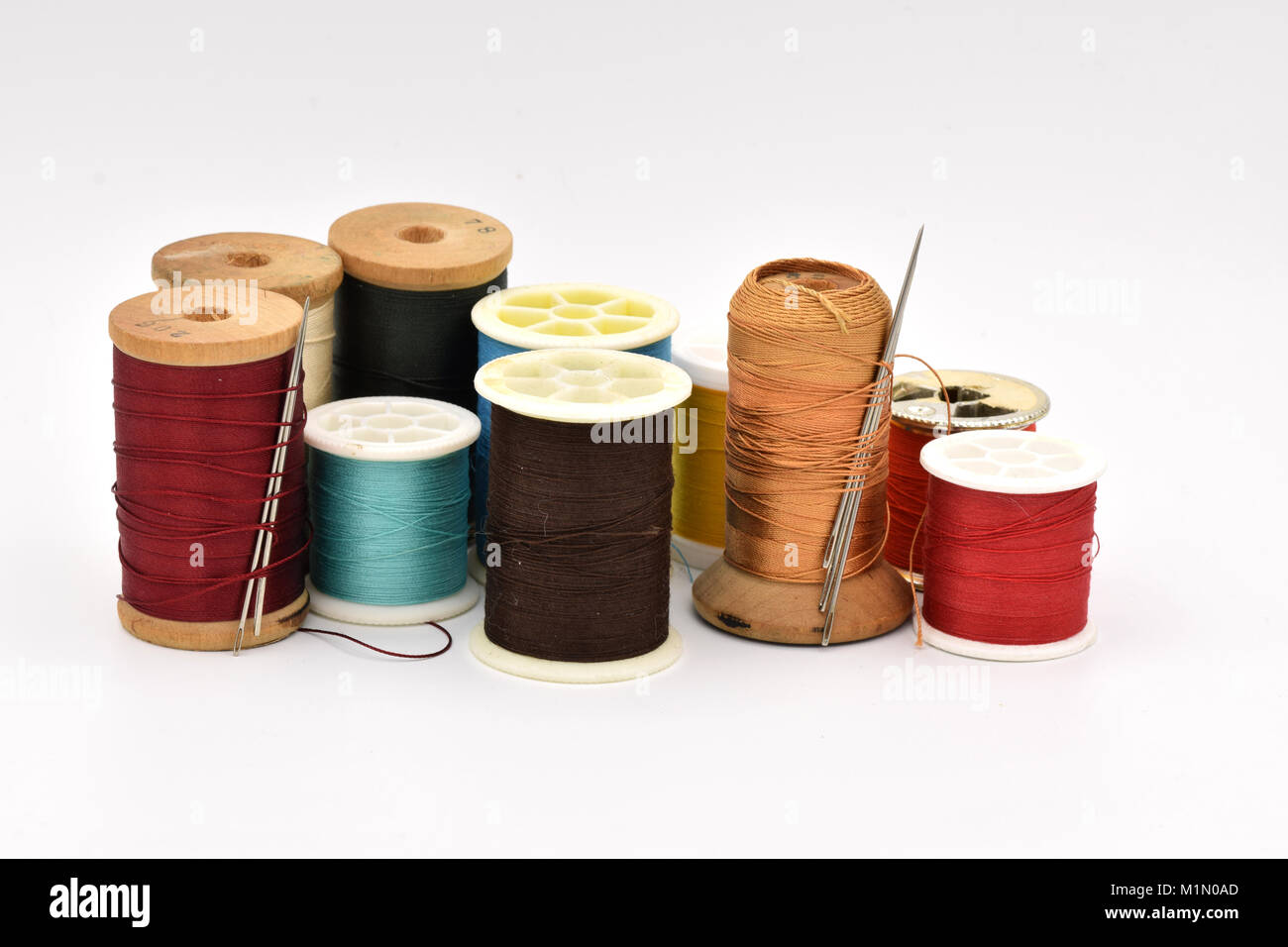 Assorted spools of colorful thread arranged on a seamless white ...