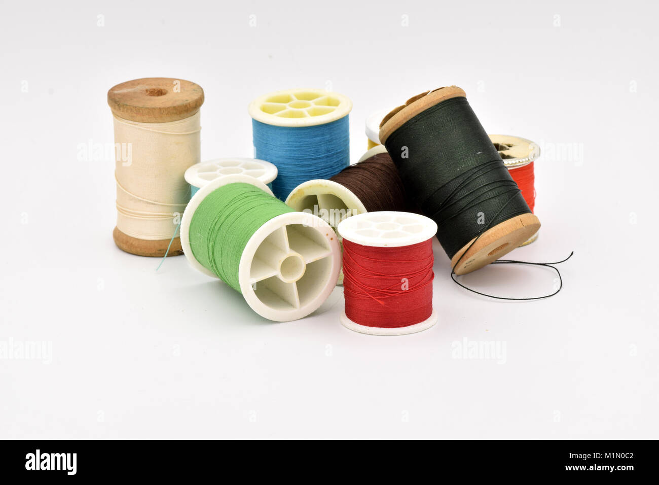 Assorted spools of colorful thread arranged on a seamless white ...