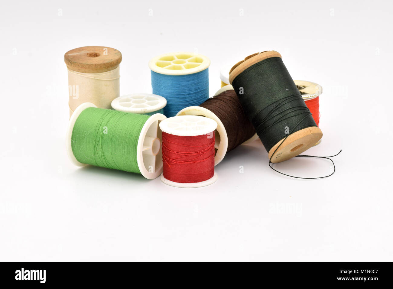 Assorted spools of colorful thread arranged on a seamless white ...