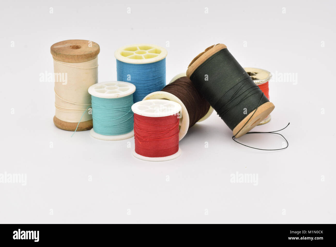 Assorted spools of colorful thread arranged on a seamless white ...