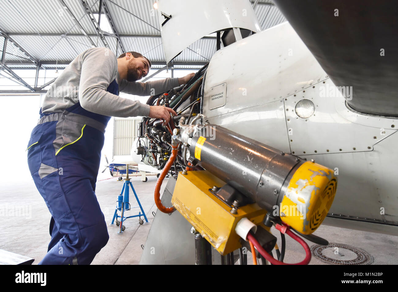 Aircraft mechanic repairs an aircraft engine in an airport hangar Stock ...