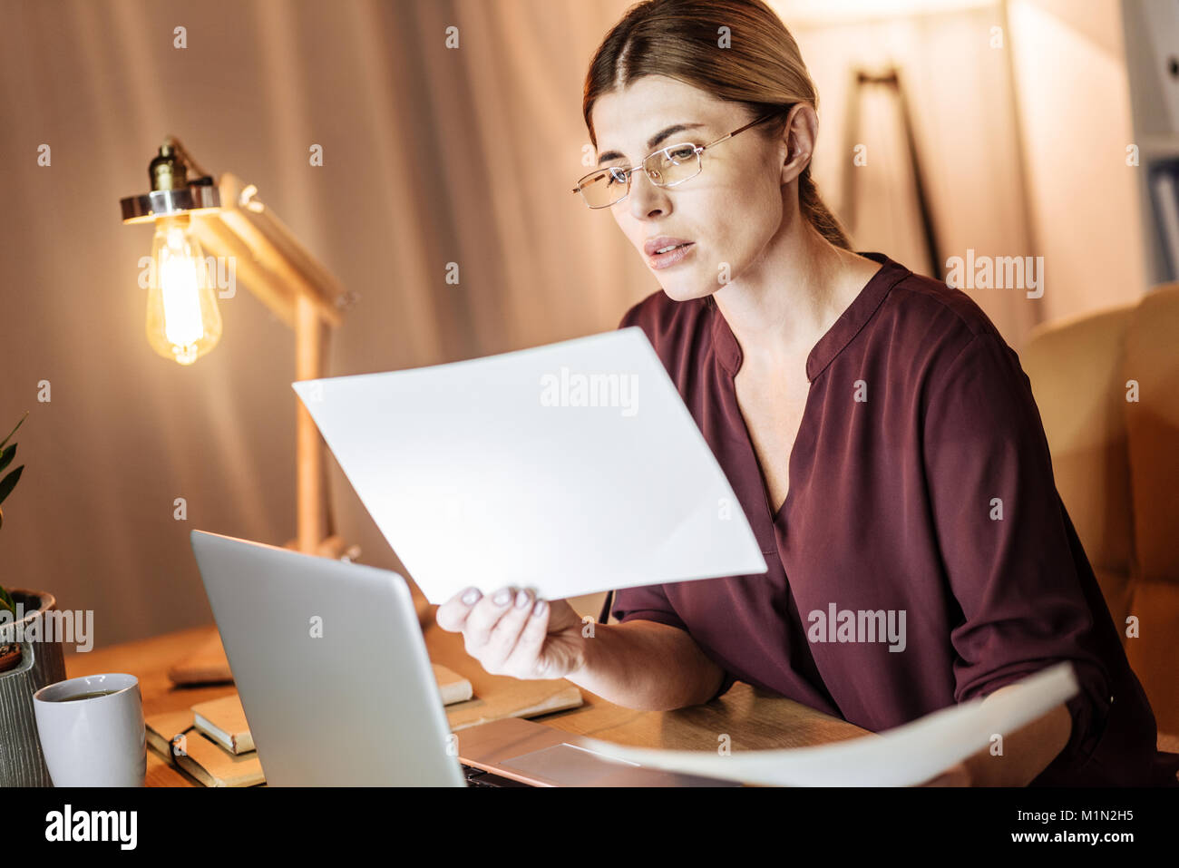 Serious woman looking at paper sheet Stock Photo - Alamy