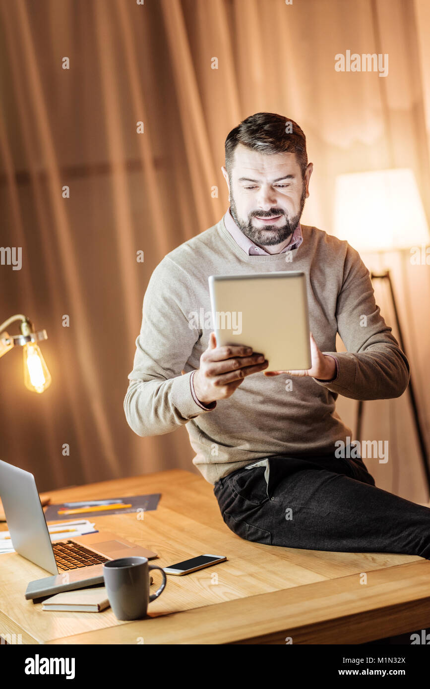 Relaxed male person using his tablet Stock Photo - Alamy