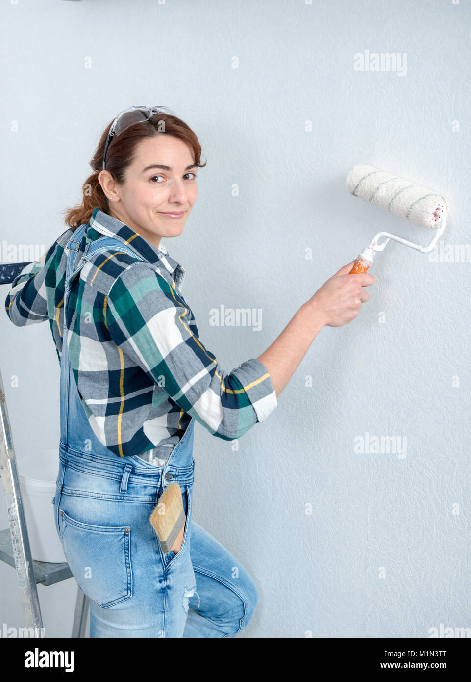 a pretty young woman painting the wall Stock Photo - Alamy