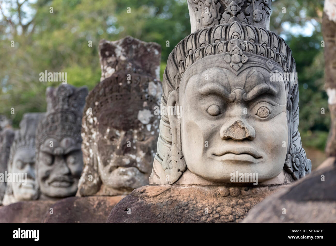 Statues of demons line the bridge in front of the South Gate of Angkor ...