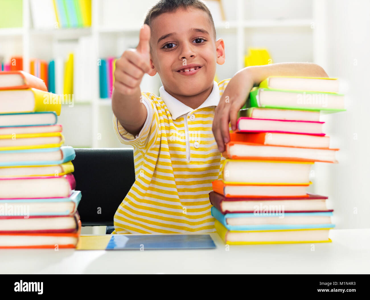 Smiling boy with pile of books Stock Photo - Alamy