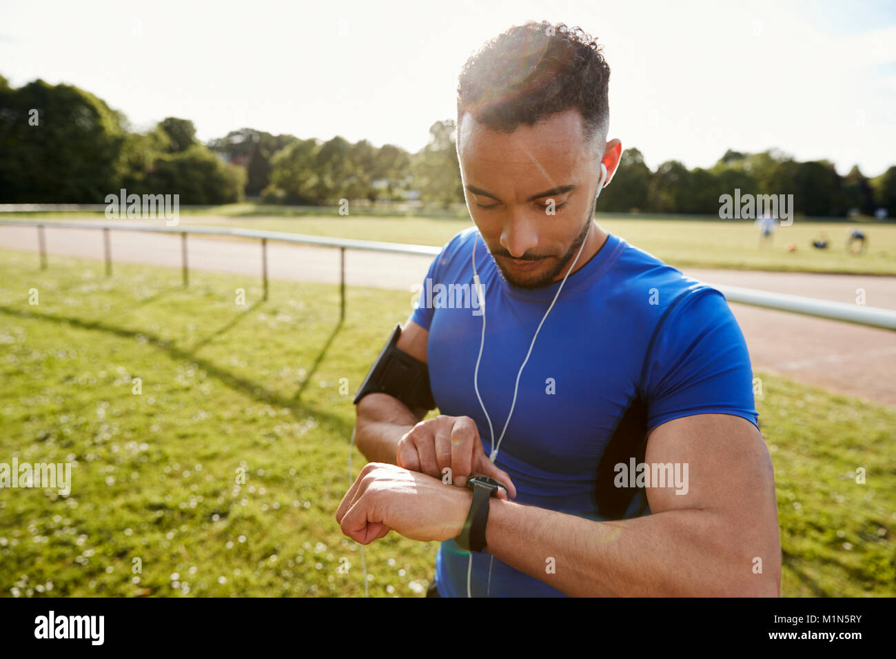 Young man at running track setting fitness app on smartwatch Stock ...