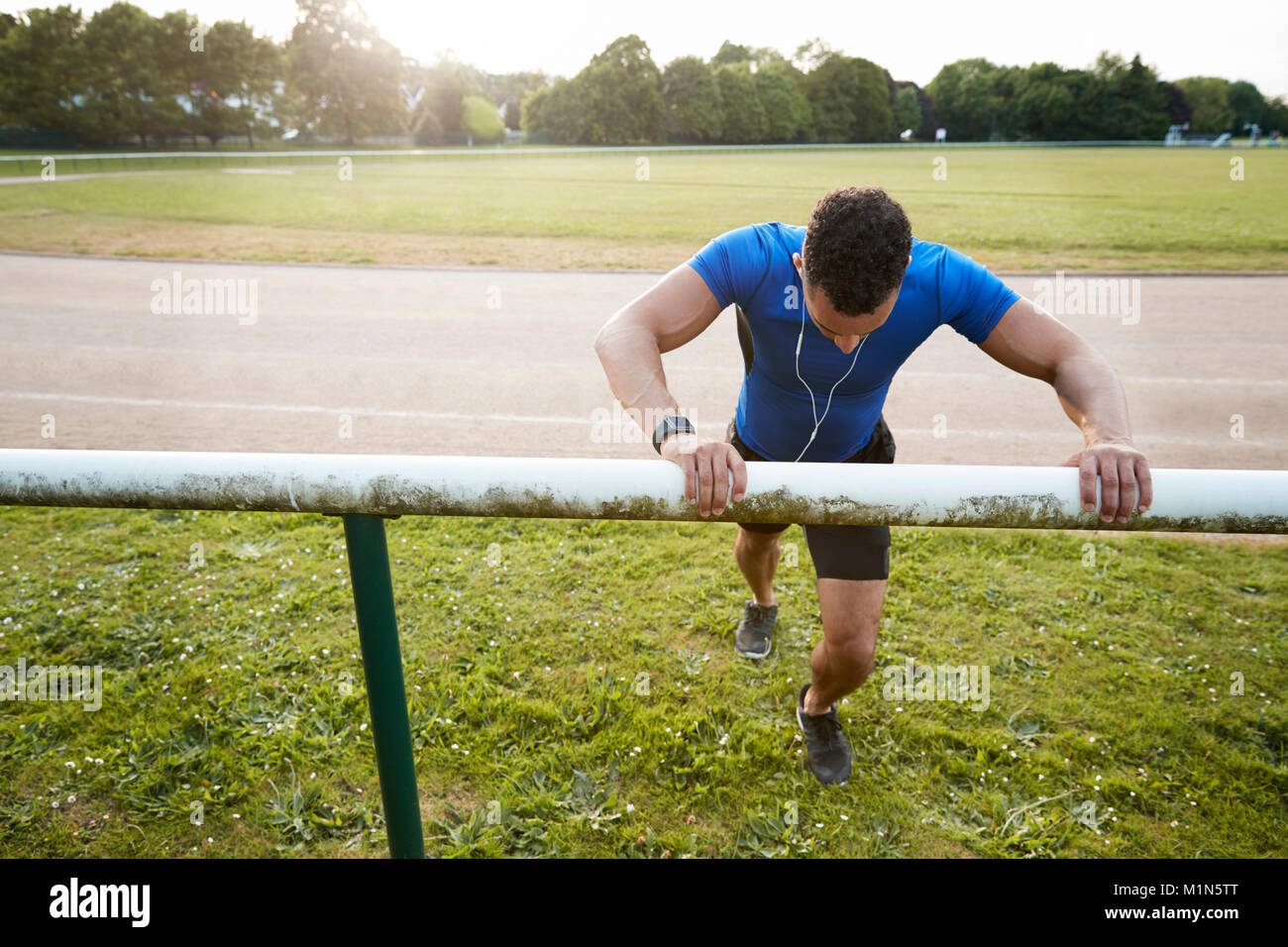 Male athlete stretching at running track, close up Stock Photo - Alamy