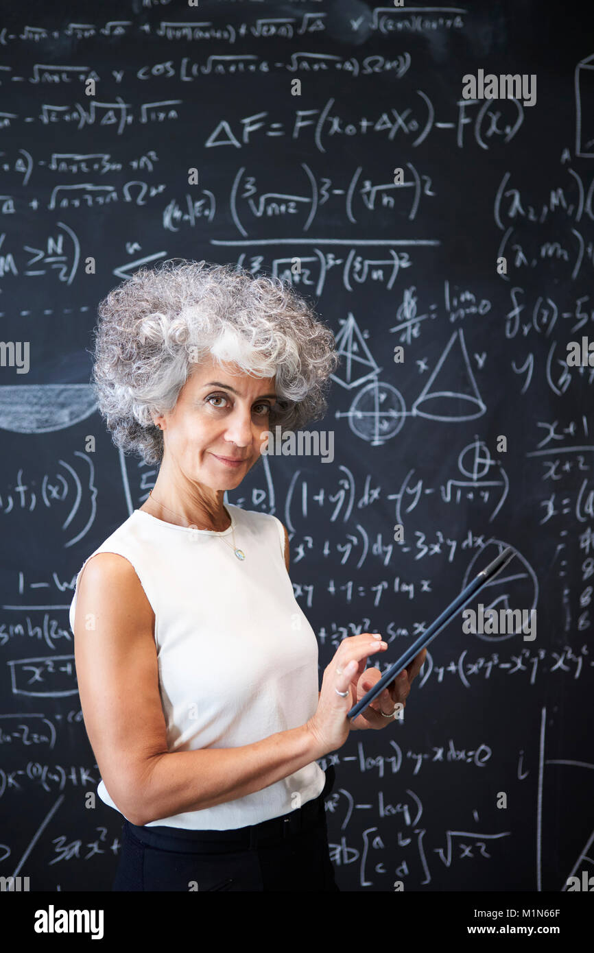 Middle aged academic woman at blackboard smiling to camera Stock Photo ...