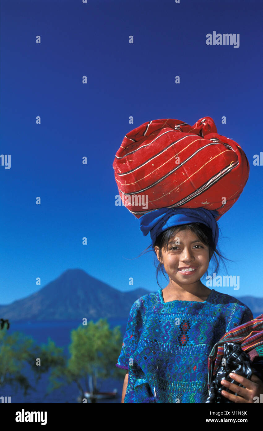 Guatemala. Panajachel. Lago de Atitlan. Volcano, maya girl carrying ...
