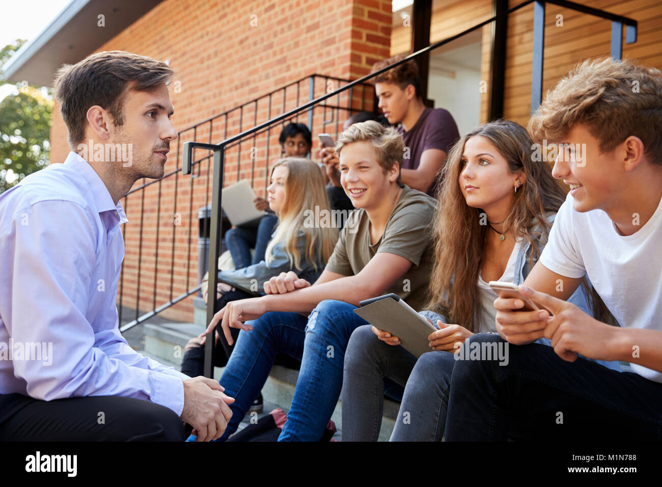 Teenage Students Talking To Teacher Outside School Buildings Stock ...