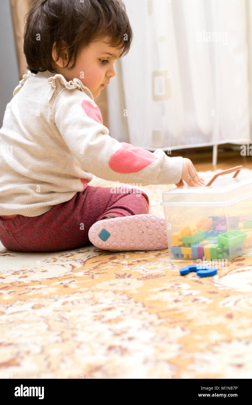 Baby girl playing on the carpet with her toys Stock Photo - Alamy