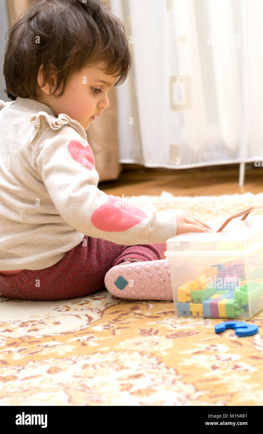 Baby girl playing on the carpet with her toys Stock Photo - Alamy
