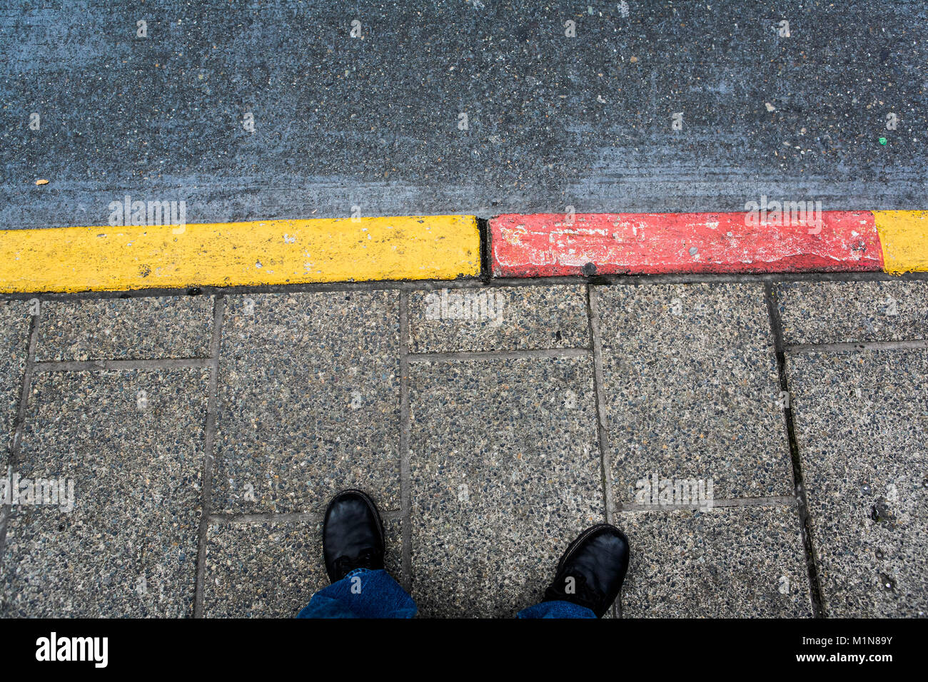 Looking down at feet standing near the brightly painted bus curb at ...