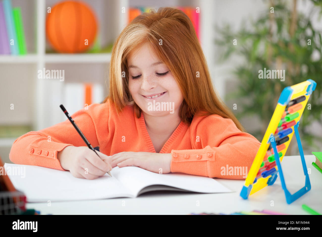 smiling red-haired girl doing her homework at home Stock Photo - Alamy