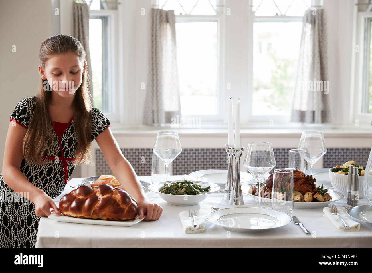 Girl placing challah bread on a table for Shabbat meal Stock Photo - Alamy