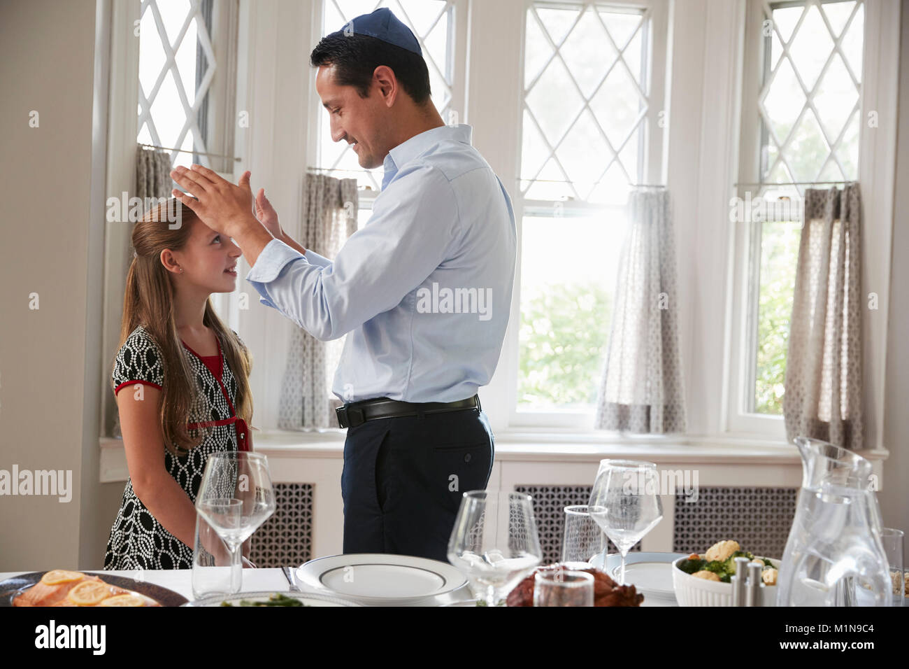 Jewish father blesses daughter by table set for Shabbat meal Stock ...
