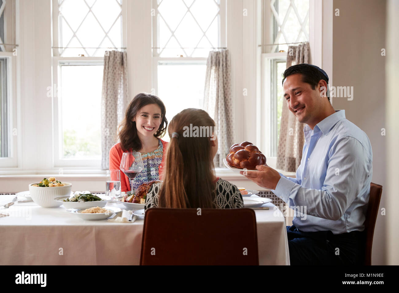 Jewish man holding challah bread at Shabbat meal with family Stock ...