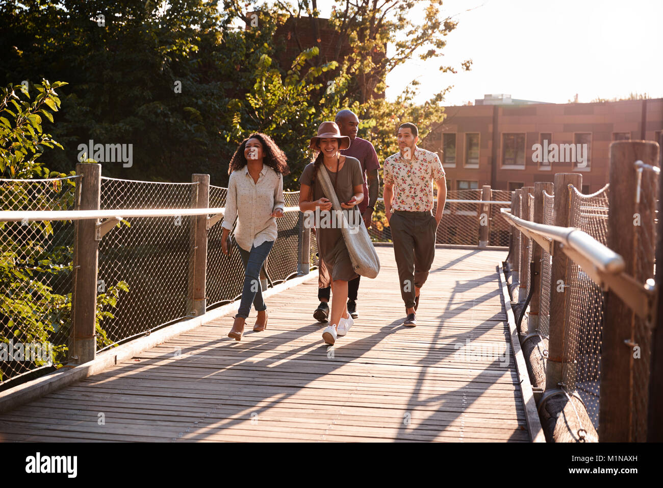 Group Of Friends Walking Along Bridge In Urban Setting Stock Photo - Alamy