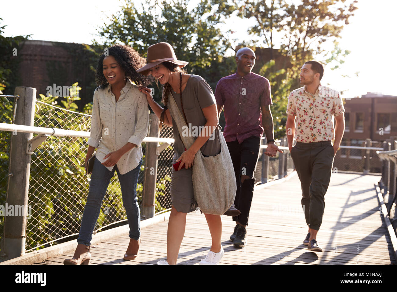 Group Of Friends Walking Along Bridge In Urban Setting Stock Photo - Alamy