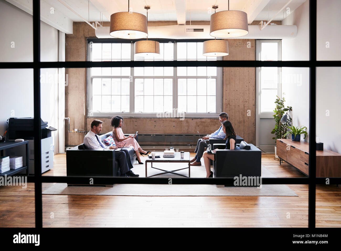 Business people in lounge meeting area, seen through window Stock Photo ...