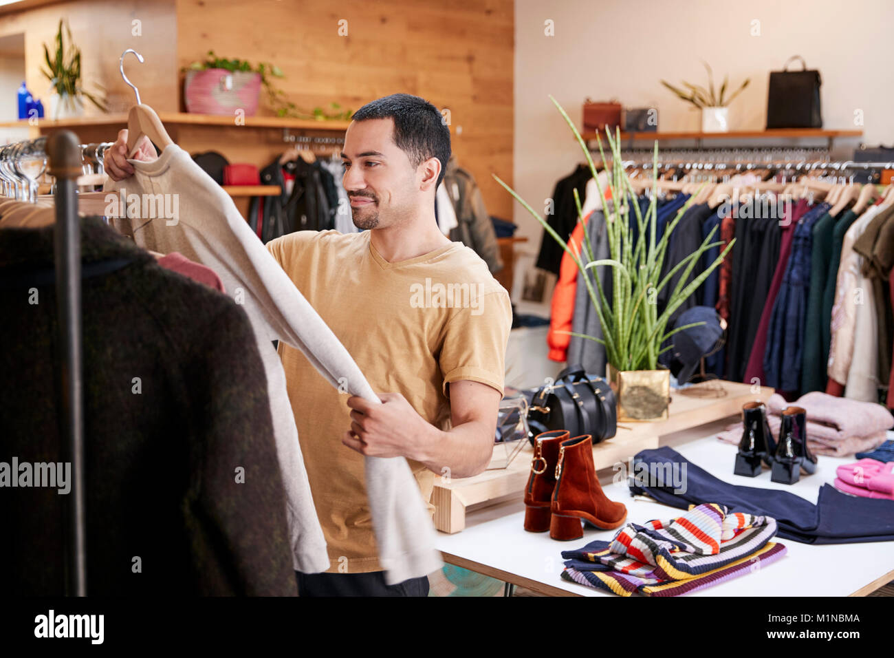 Young Hispanic man looking at clothes in a clothes shop Stock Photo - Alamy
