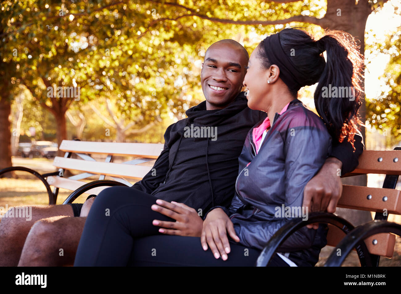 Young black couple sitting on bench in Brooklyn park Stock Photo - Alamy