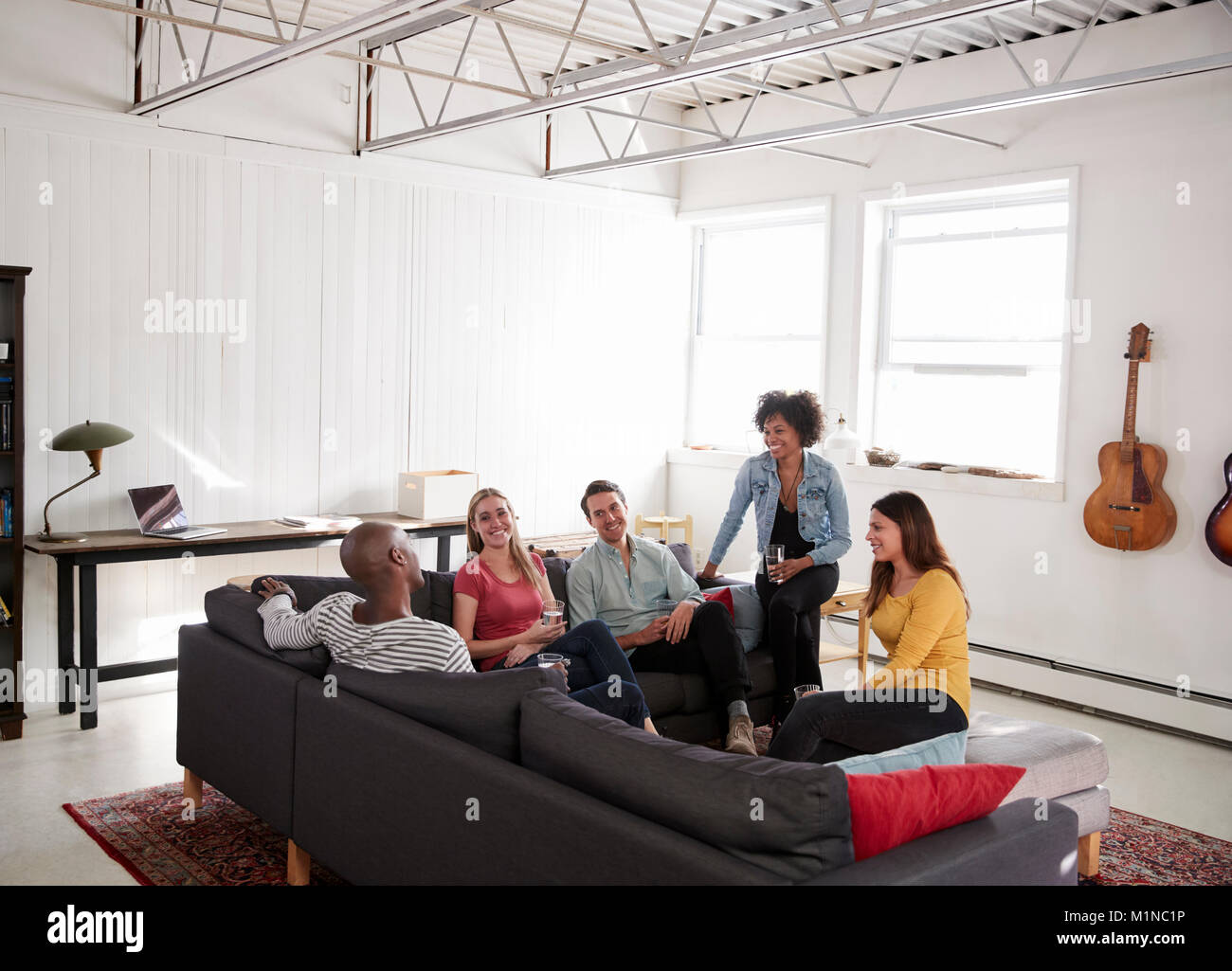 Five young friends socialising in a New York loft apartment Stock Photo ...