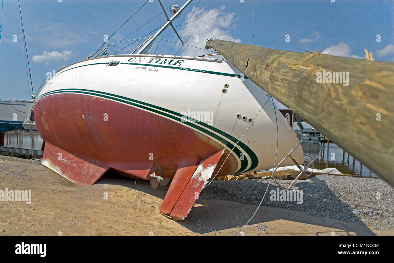 A downed power pole lays on top of a damaged sailboat that was washed ...