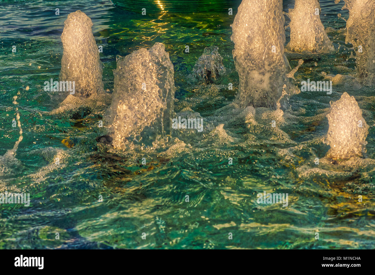 Spurts in the green water of a fountain at sunset Stock Photo - Alamy
