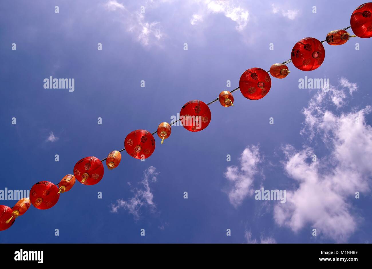 A string of traditional red Chinese lanterns isolated against a blue ...