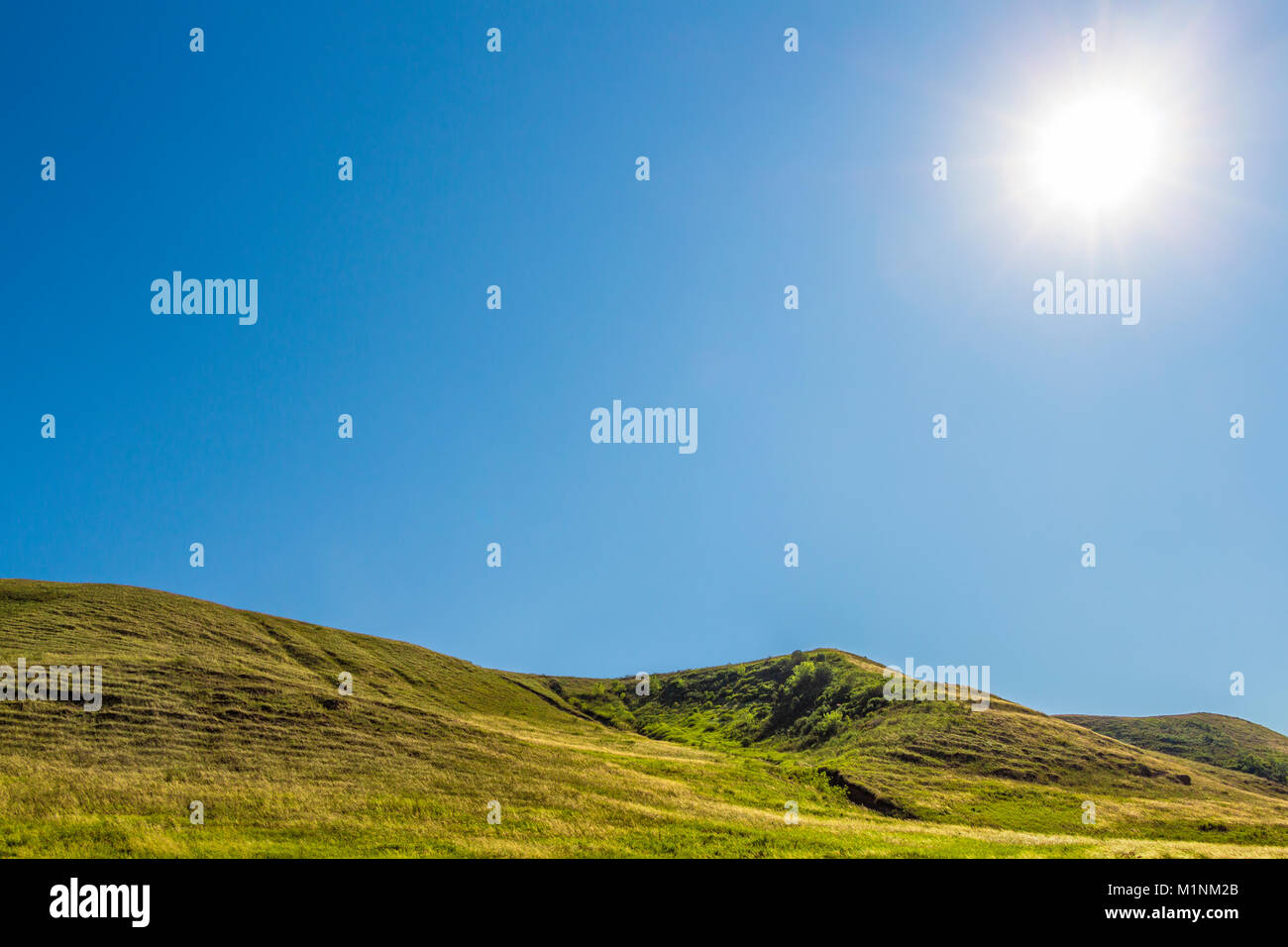 The natural sun against the blue sky above the surface of the hilly ...