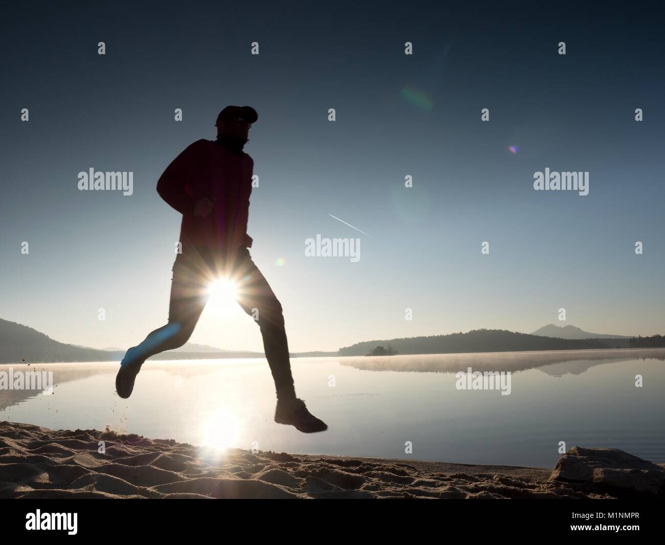 Exercising on the lake beach at sunset, big sun at horizon Stock Photo ...