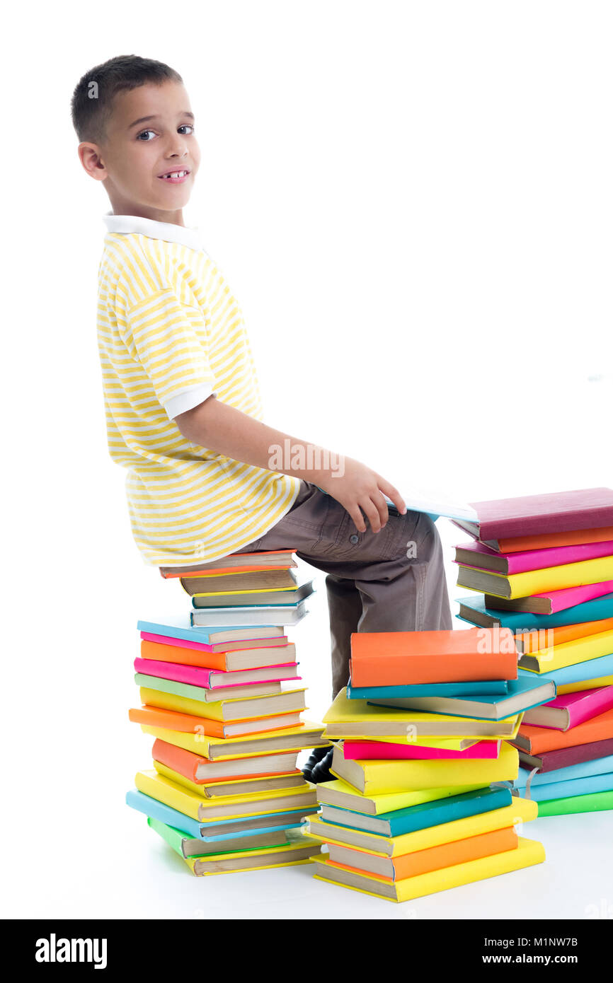boy sitting on a pile of books and holding one book in his hands Stock ...